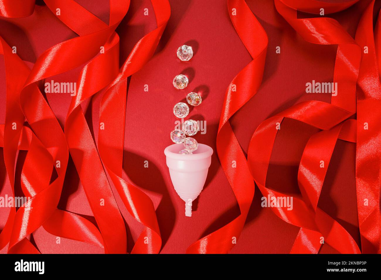 Pink menstrual cup, transparent crystals like blood drops and roll red ...