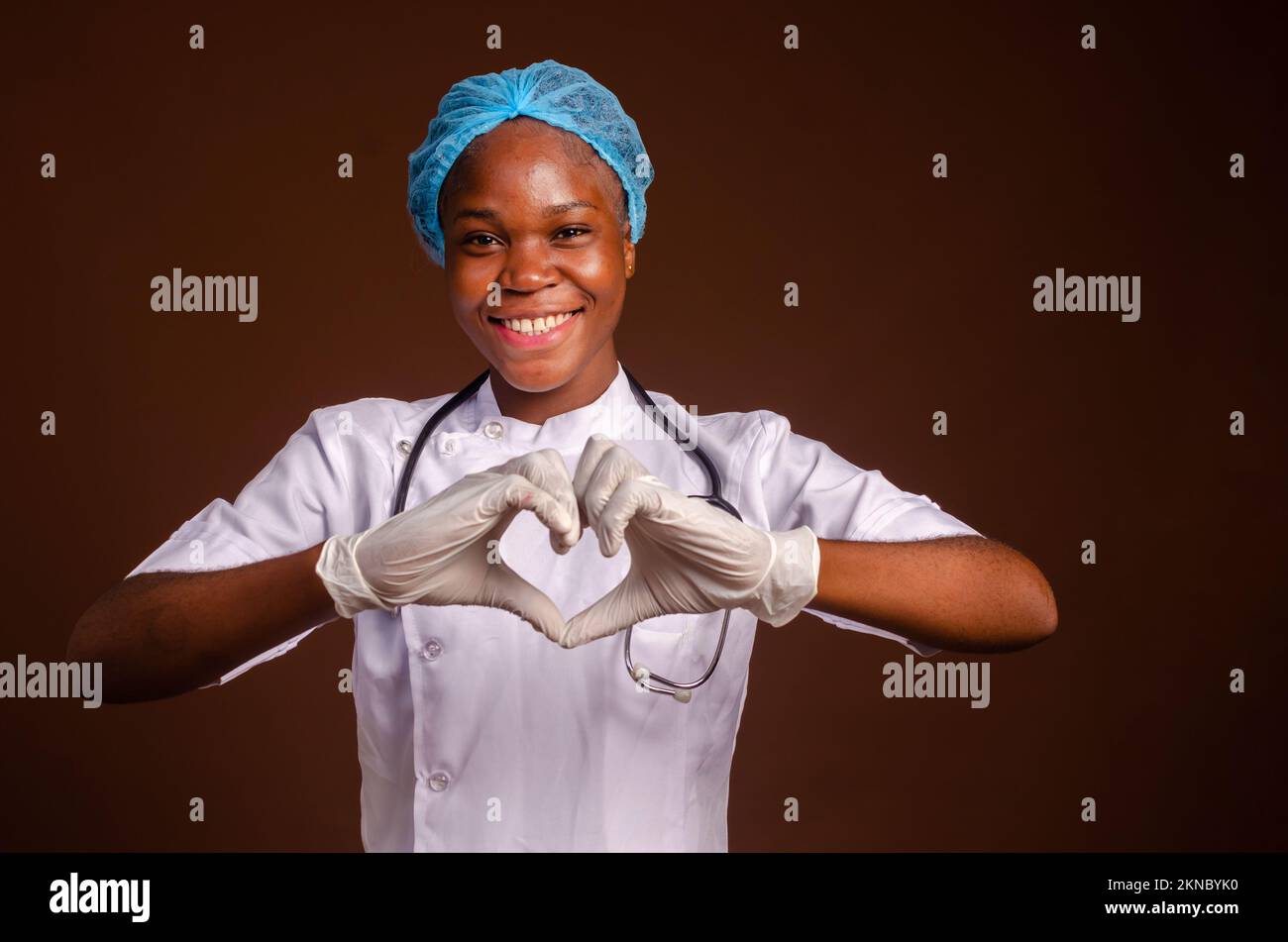 A smiling Nigerian female medic with a stethoscope showing a heart ...