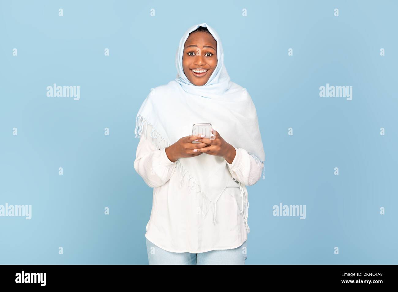 Emotional black muslim woman using cellphone while reading great ...