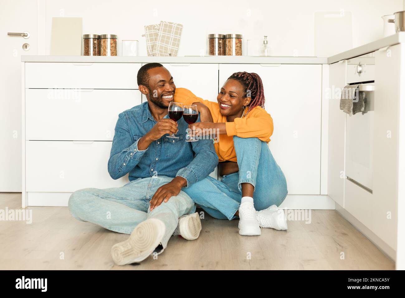 Romantic african american couple drinking red wine while sitting on ...