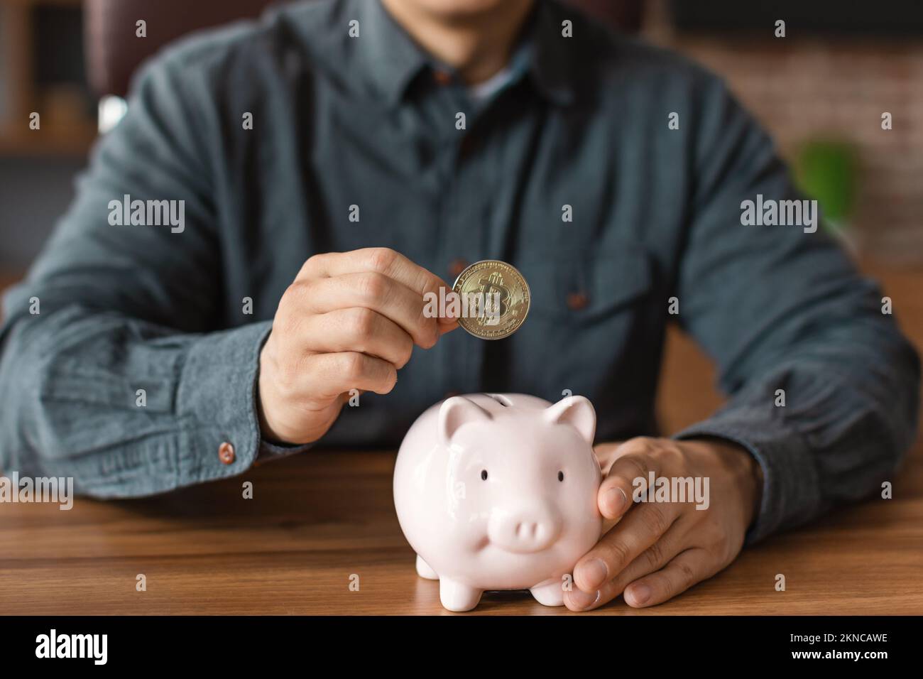 Mature asian male manager puts bitcoin coin in piggy bank in home ...