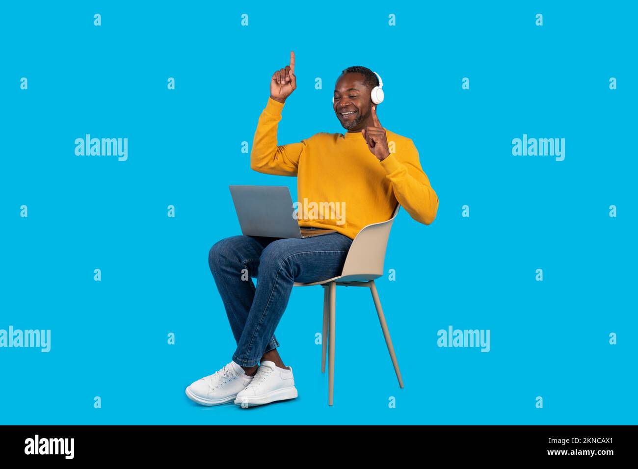 Happy black man using laptop and wireless headphones on blue Stock ...