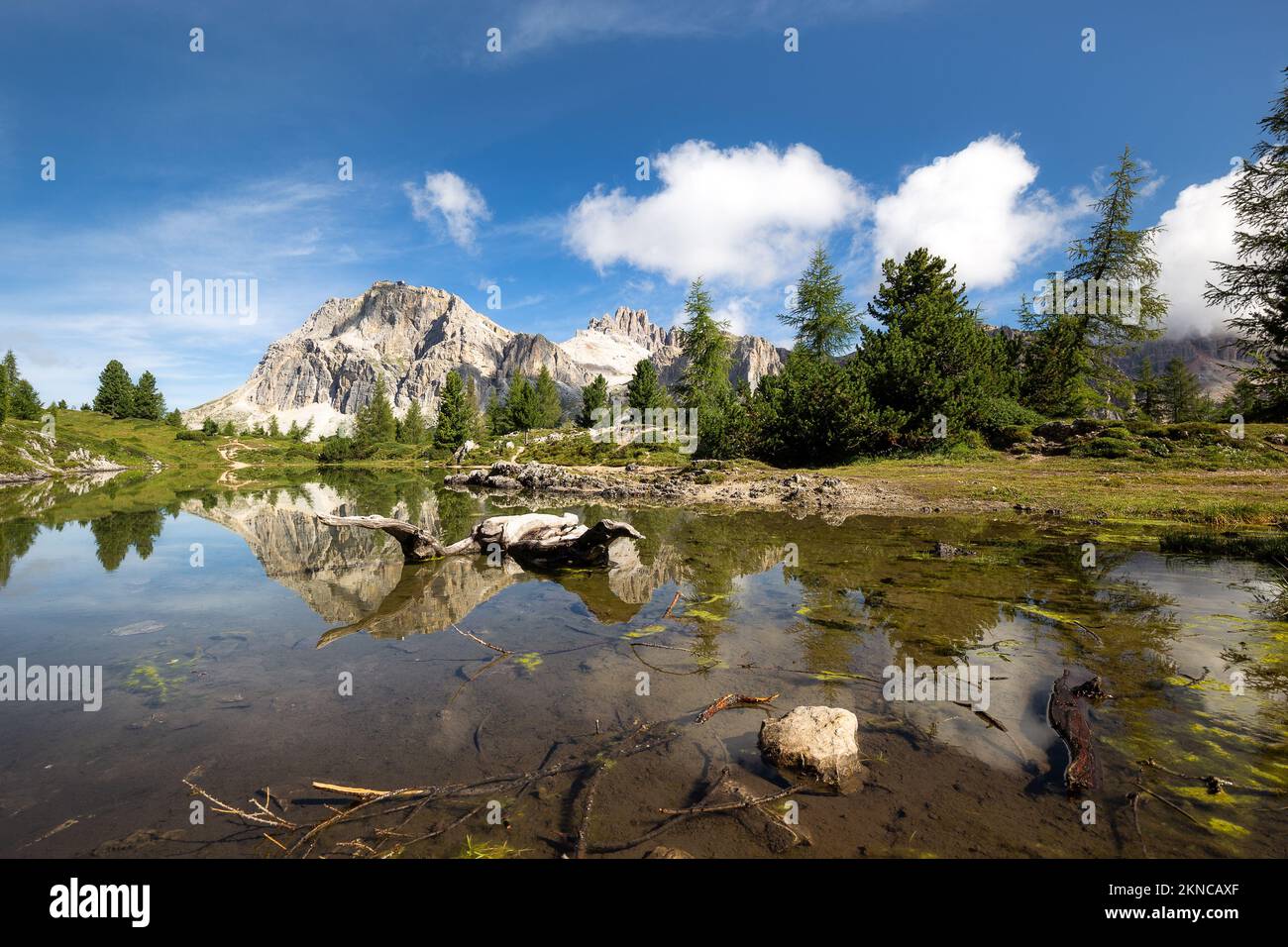 A scenic shot of a small lake in mountains with a rocky hill and trees ...