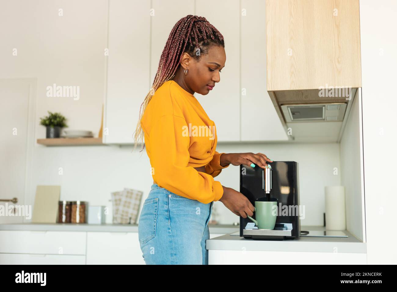 Young african american woman using modern coffee machine, making drink ...
