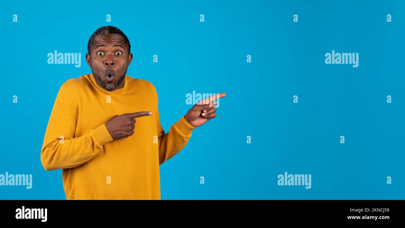 Shocked black man pointing at copy space over blue Stock Photo - Alamy