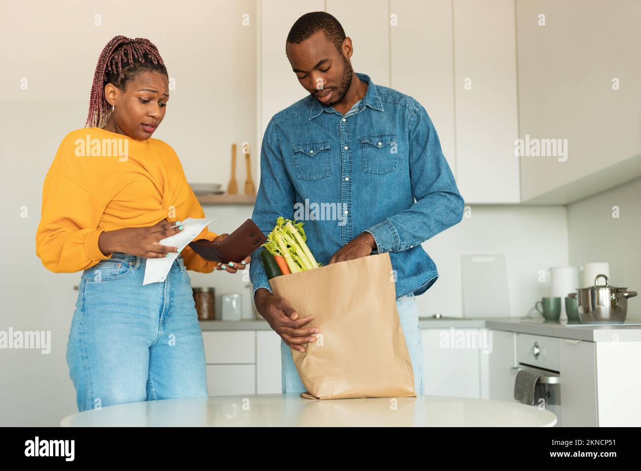 Black couple unpacking products from market in kitchen, woman looking ...