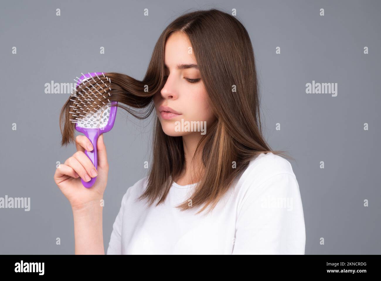 Girl combing hair. Beautiful young woman holding comb straightened hair ...
