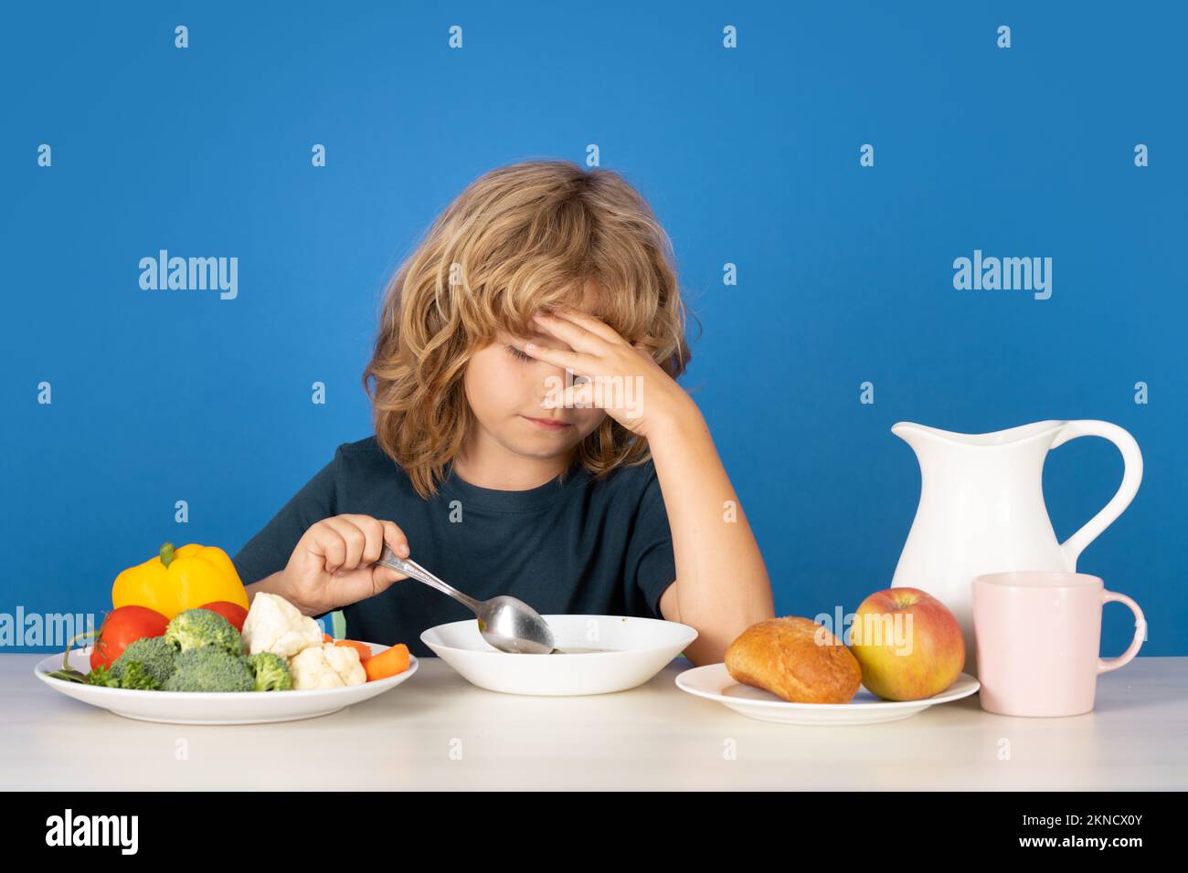 Bad appetite. Sad kid eating healthy food on studio iosolated ...
