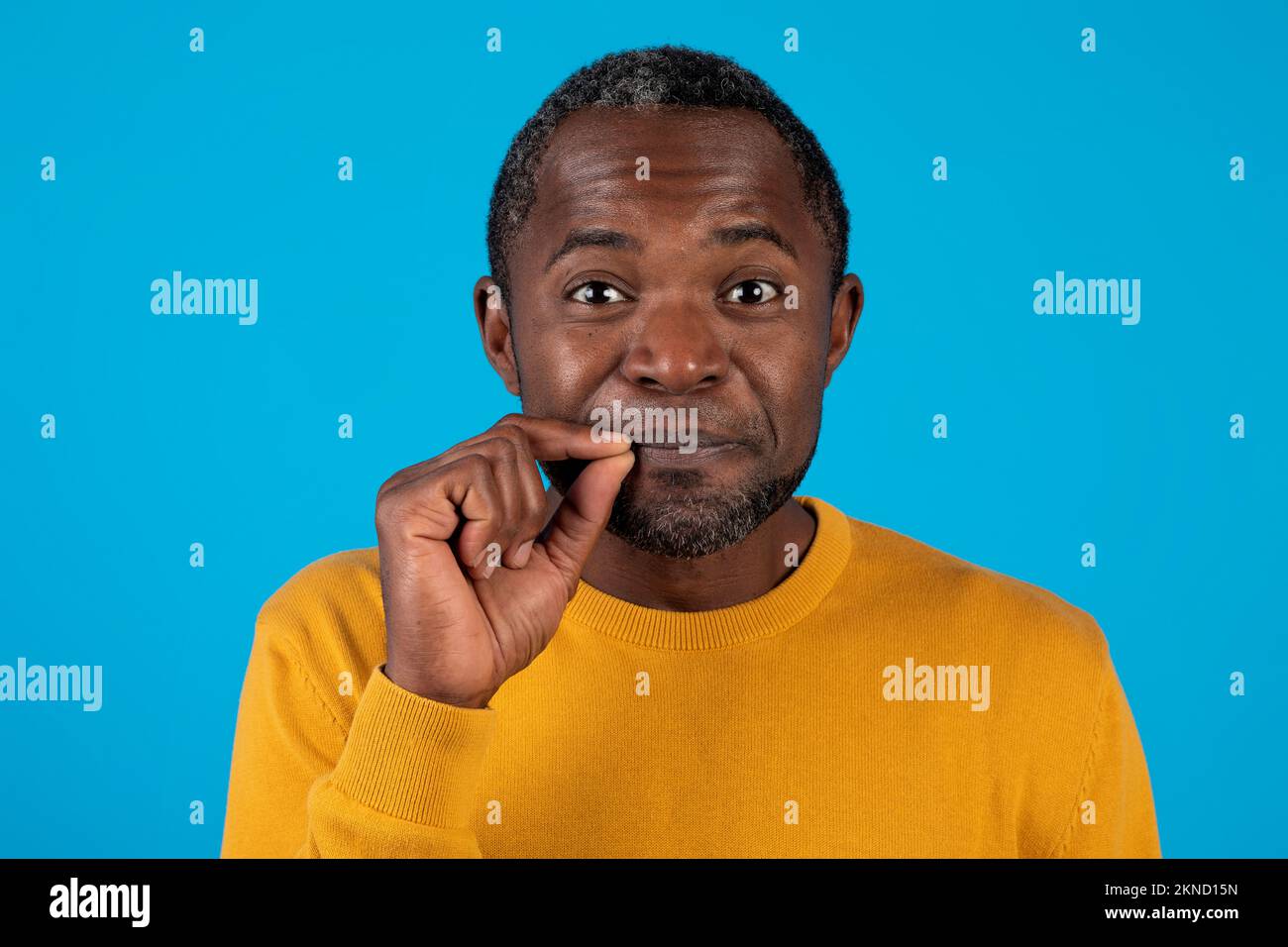 Black man showing mouth shut as zip with fingers Stock Photo - Alamy