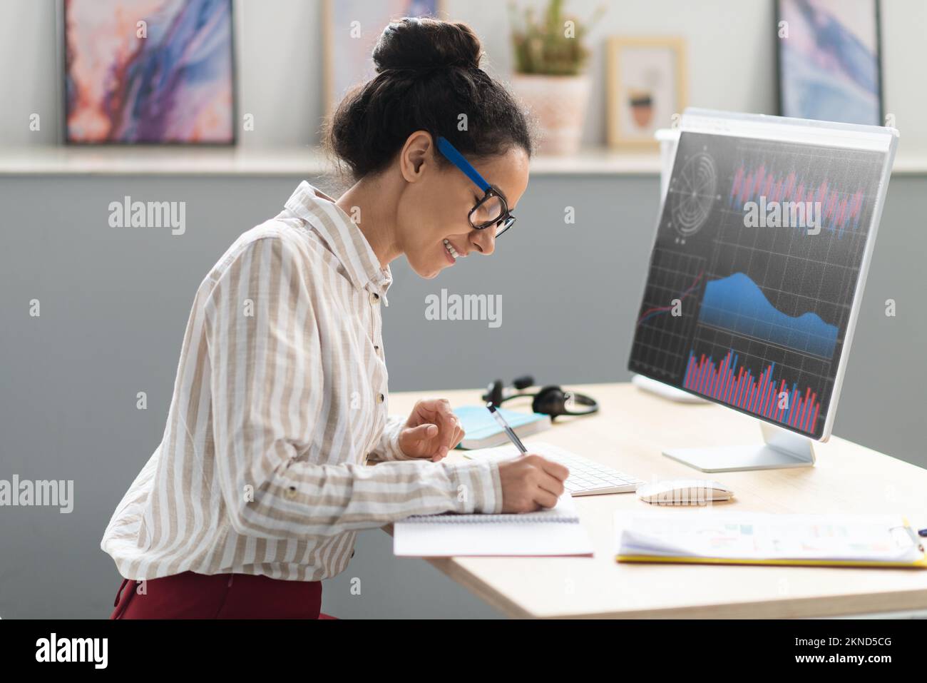 Happy businesswoman taking notes and analyzing indexes, financial ...