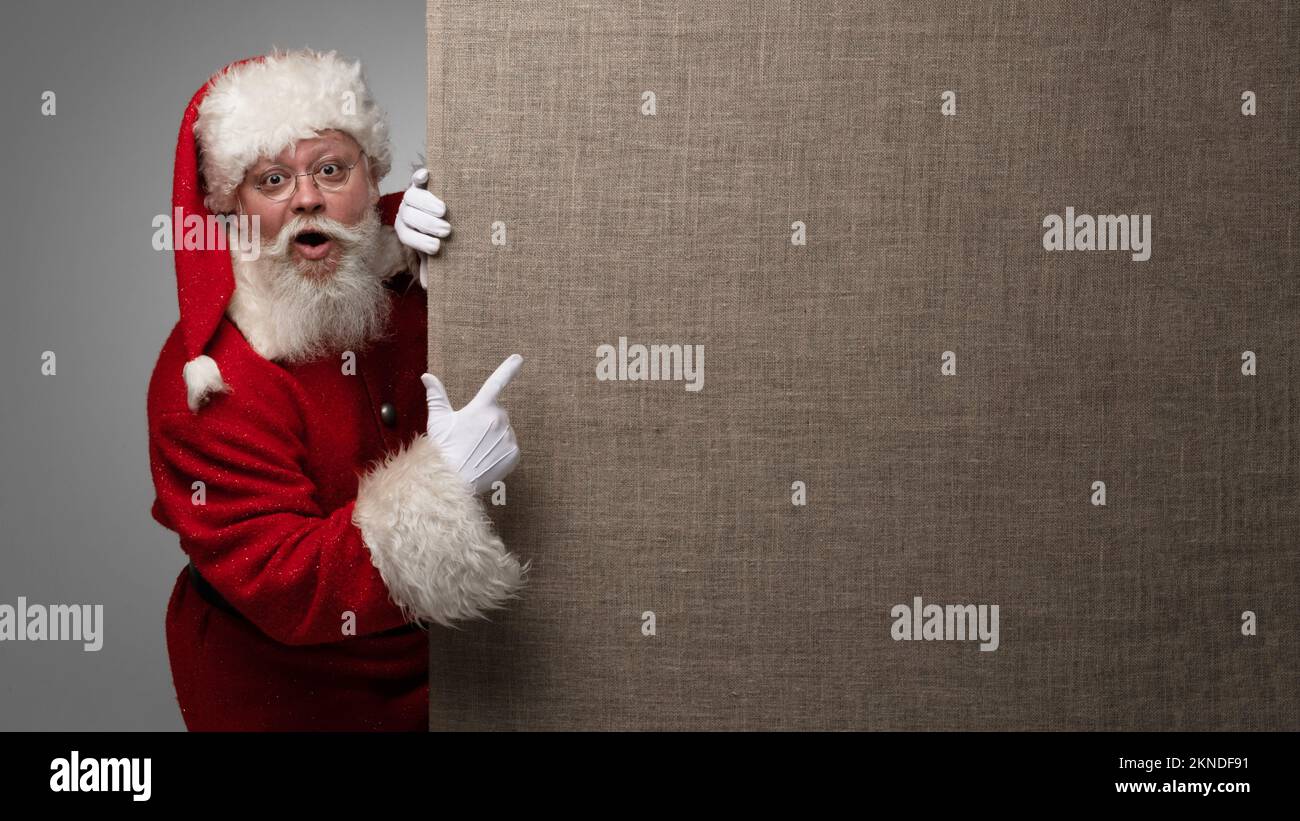 Santa Claus pointing at fabric billboard with copy space for text Stock ...