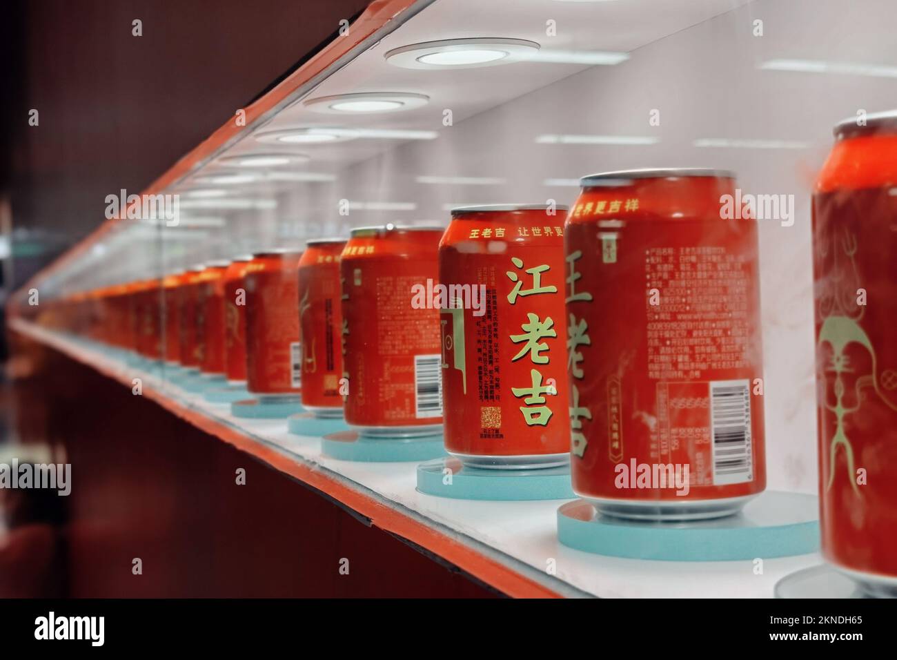 A row of red drink cans in a shop with different family names in ...