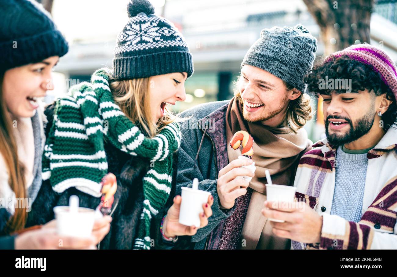 Happy friends having fun eating sweets at Christmas market on winter ...