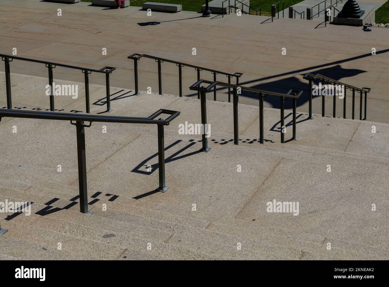 Metal railings at the marble steps on a front of a grass field in a ...