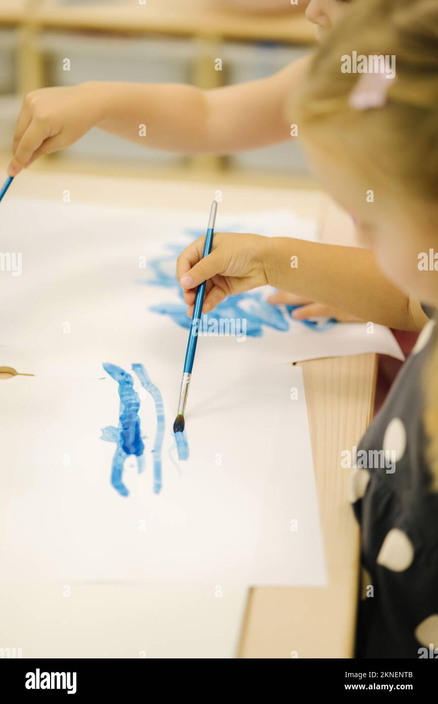 Children painting in kindergarden. Hand of little girl hold brush and ...