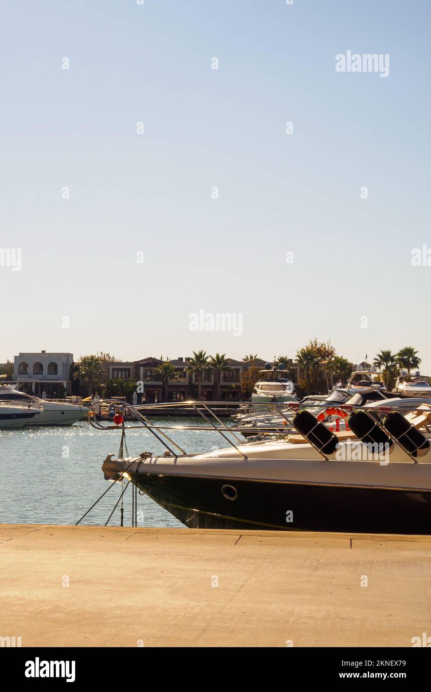 A vertical shot of empty boat anchored at the port on blue sky ...