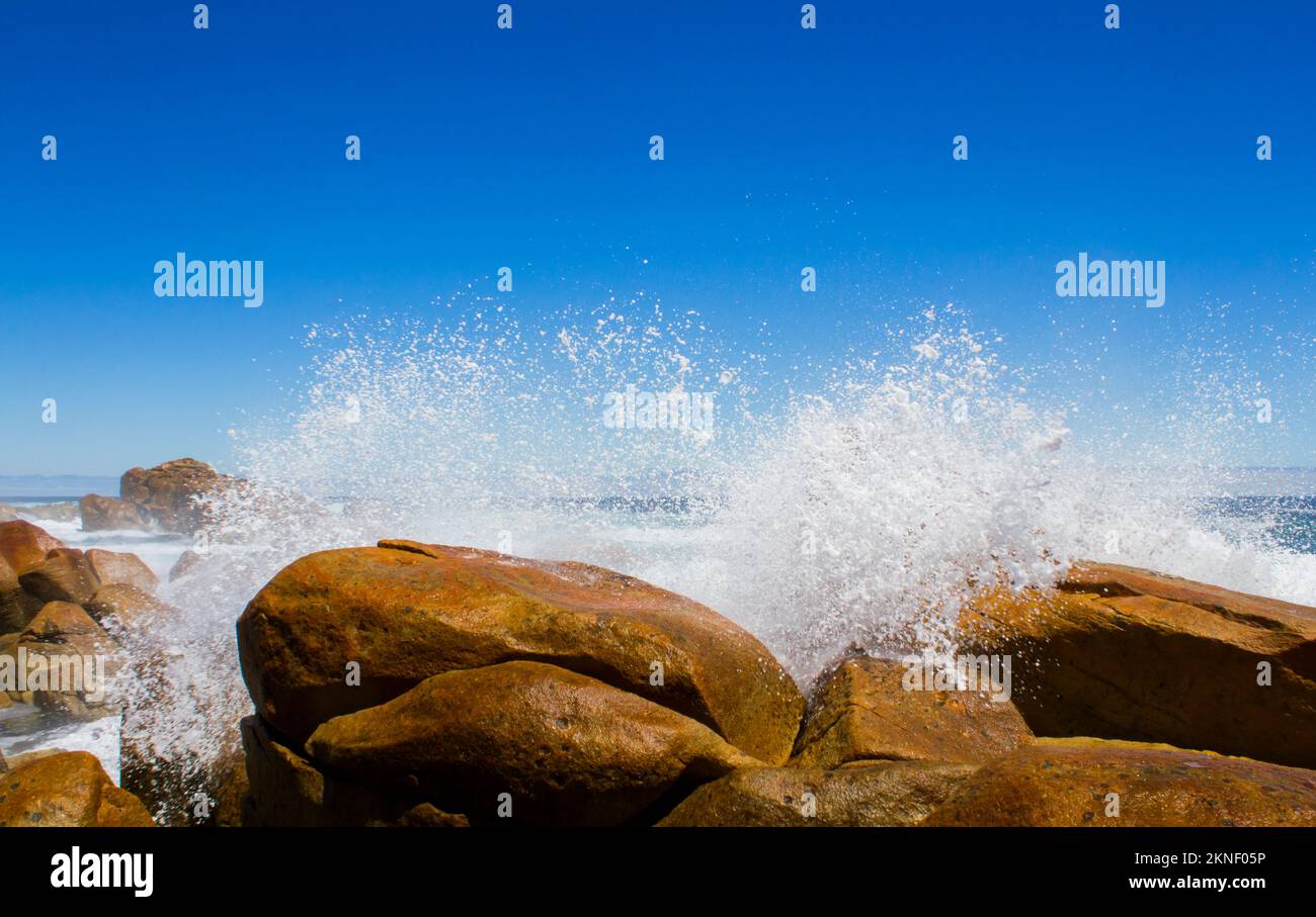 Water and rocks collide on a clear blue day at Granville Harbour ...