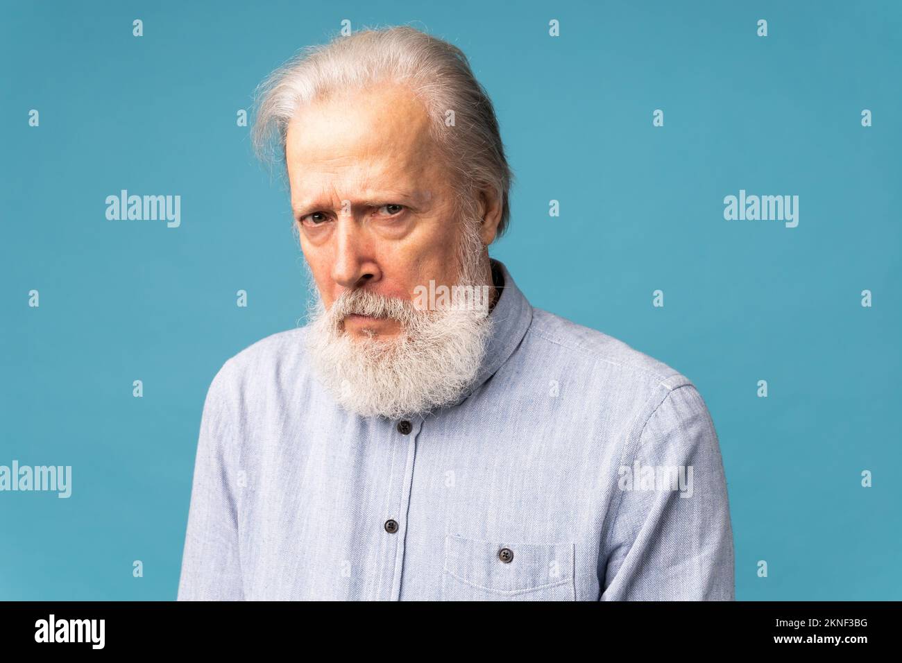 Portrait of unhappy grumpy pissed off senior mature man on blue ...
