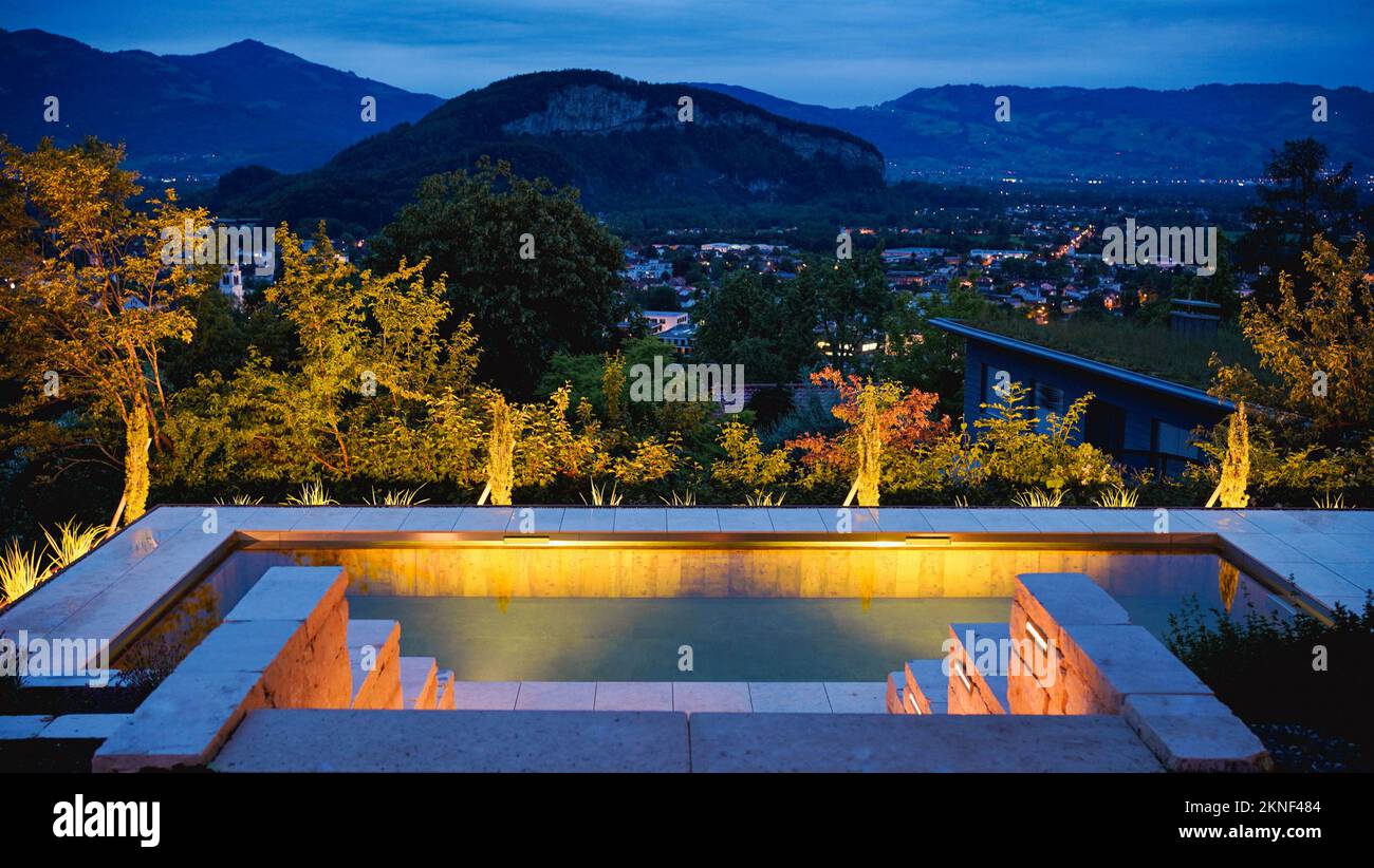 Evening view of a illuminated swimming pool with wooden walls in a ...