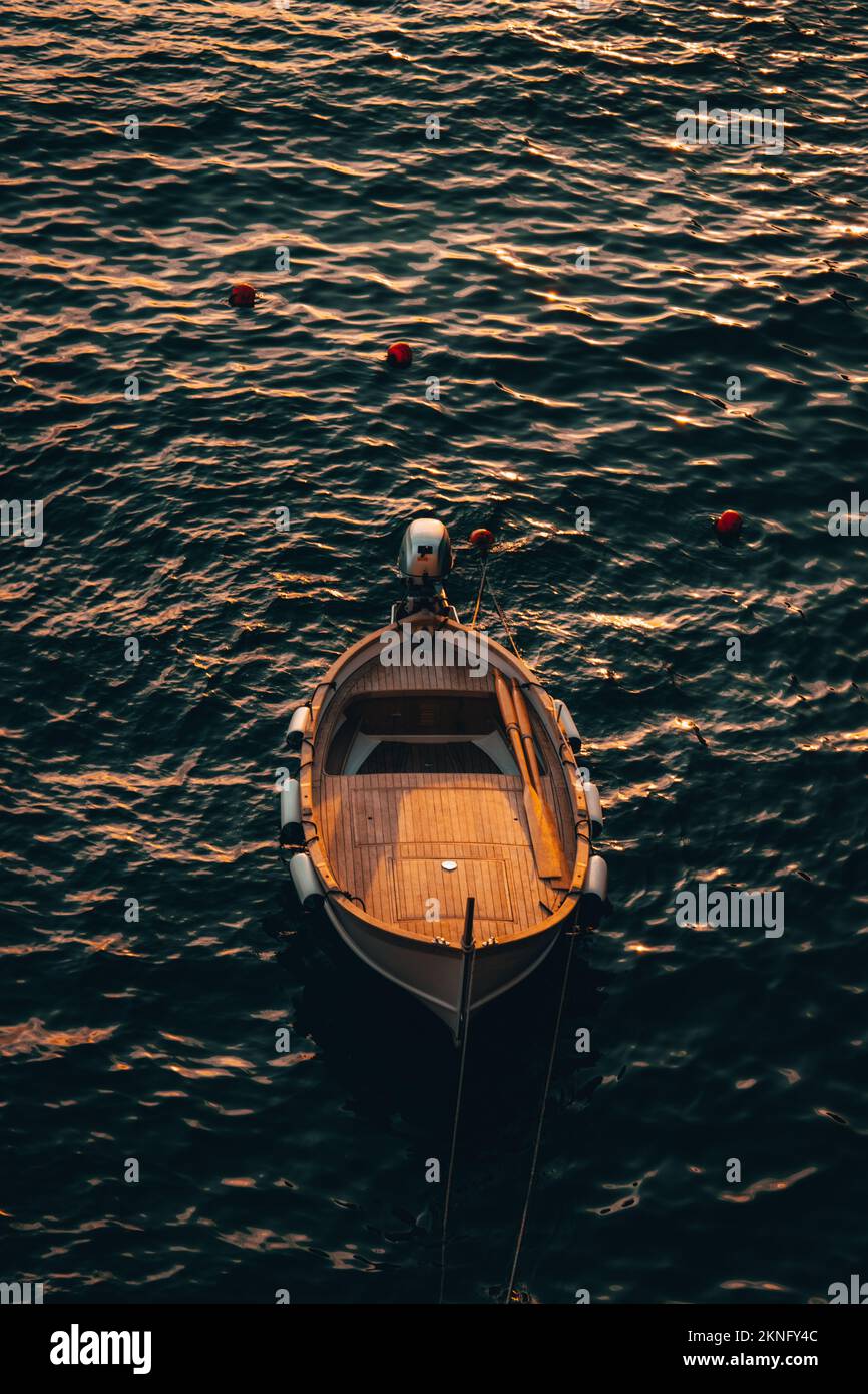 A vertical shot of a wooden dinghy boat in the ocean at sunset Stock ...