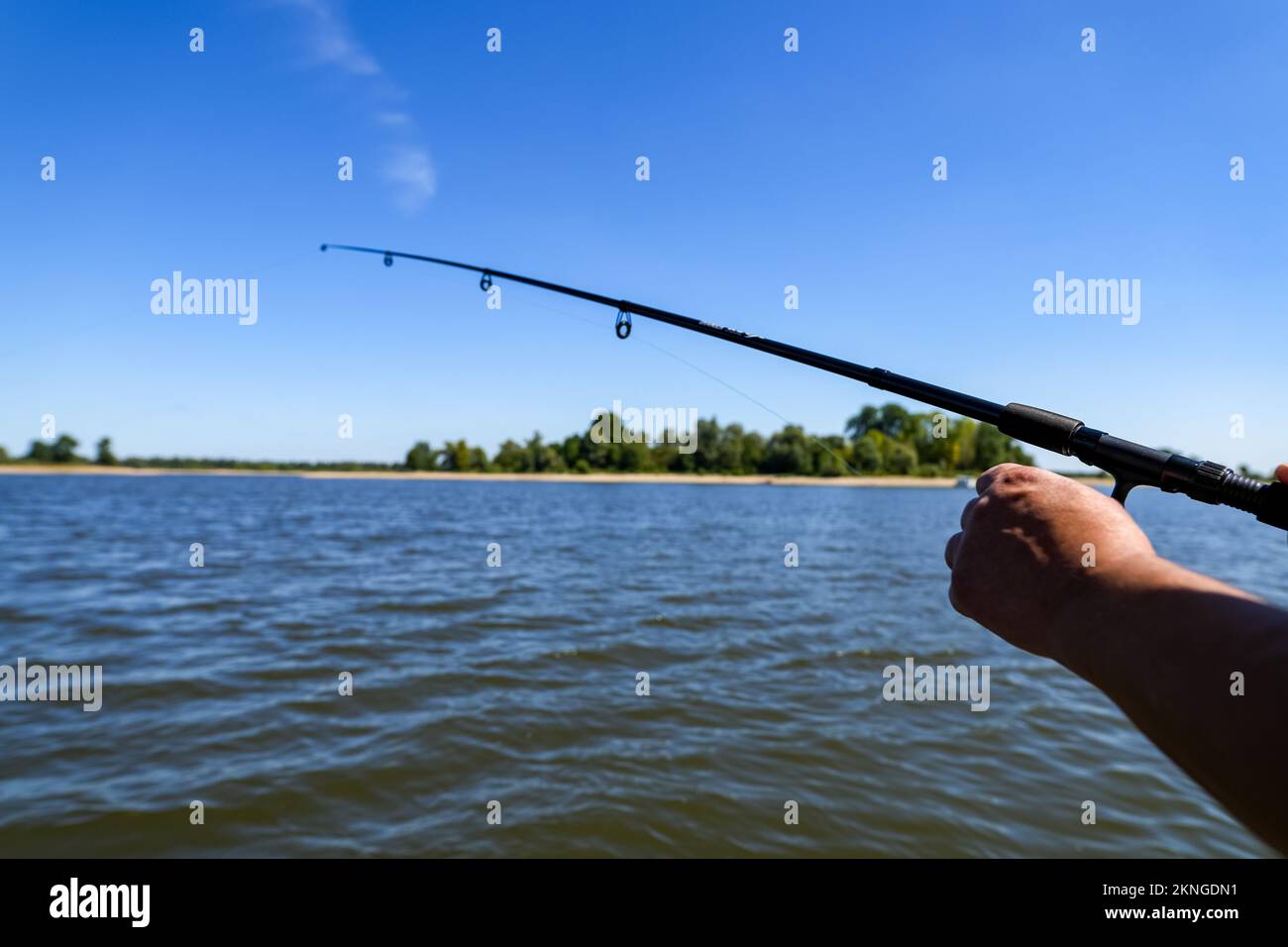 A scenic view of a person holding a fishing rod while fishing next to ...
