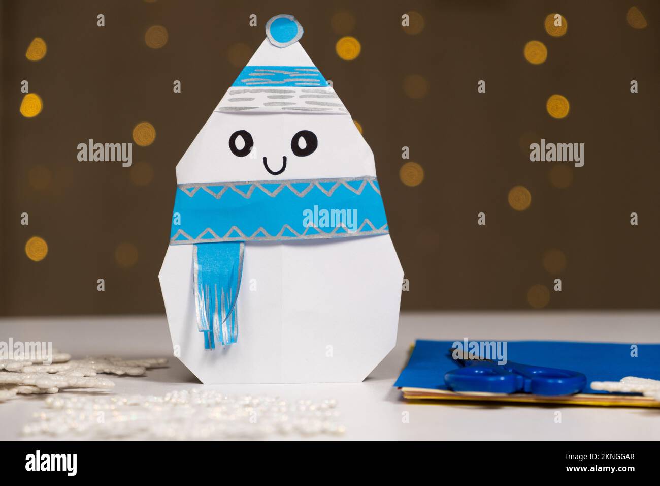 Christmas crafts origami snowman from paper on a background of bokeh ...