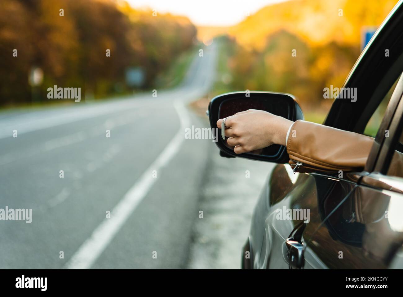a hand sticking out of the window of a car parked on the roadside in ...