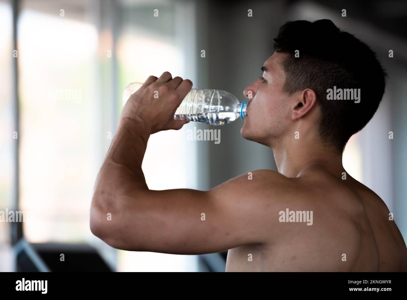 Young caucasian healthy sports man drinking water in the sport gym ...