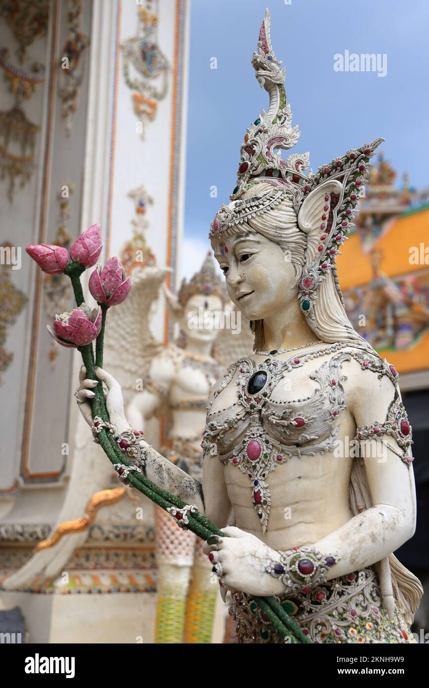 A pearl white statue of NAGA, a Thai mythical goddess holding a bunch ...