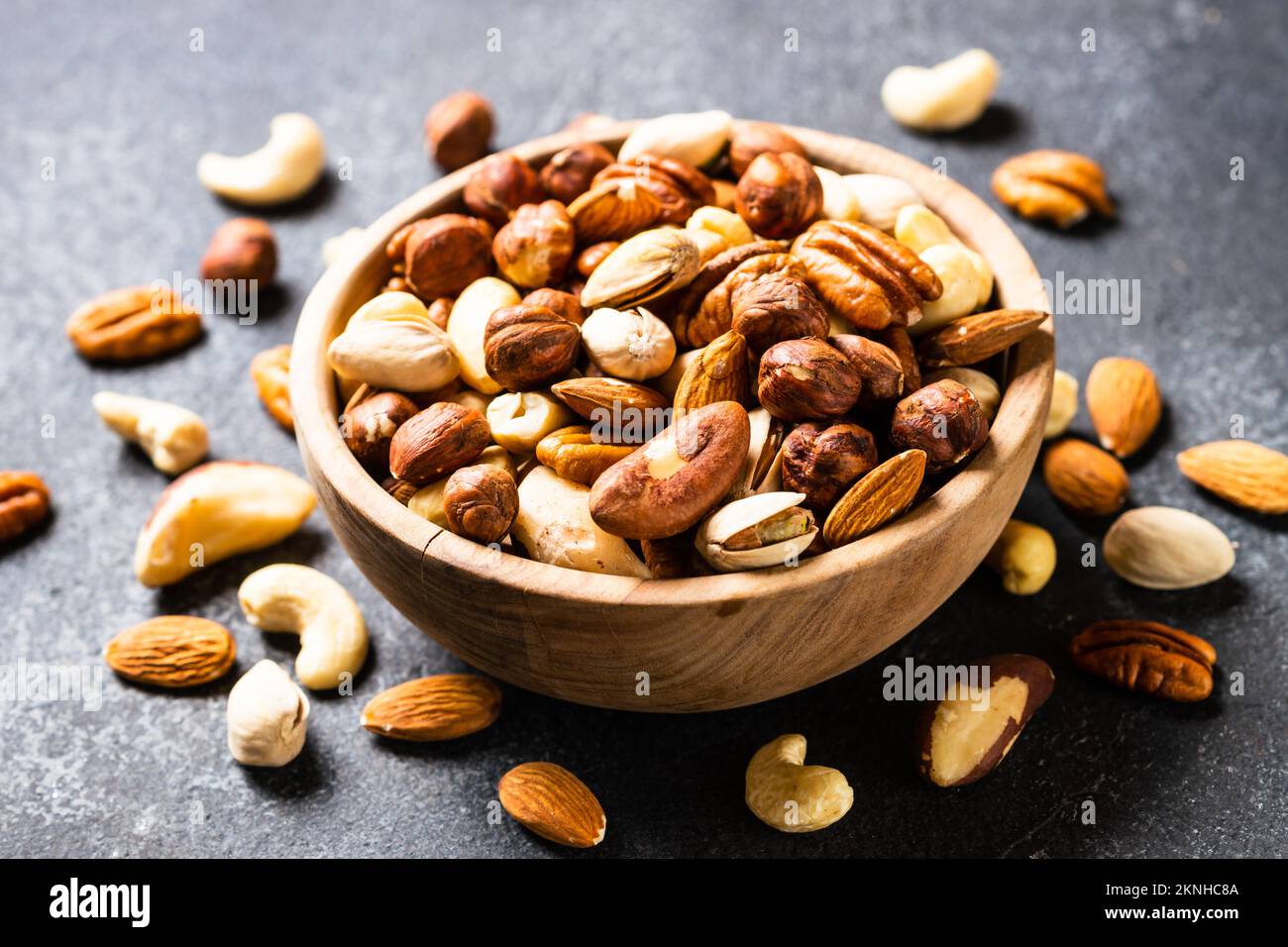 Assortment of nuts in wooden bowl on dark stone table. Cashew ...