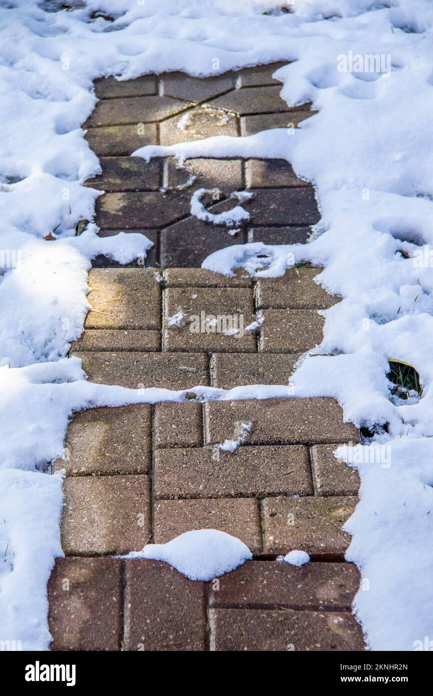 Paving stone fake brick sidewalk in the melting snow - vertical ...