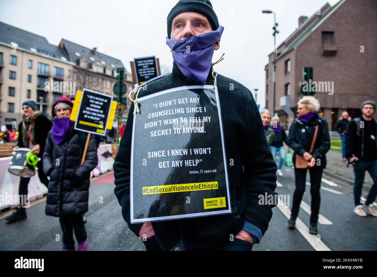 A man is seen wearing a placard around his neck from Amnesty ...