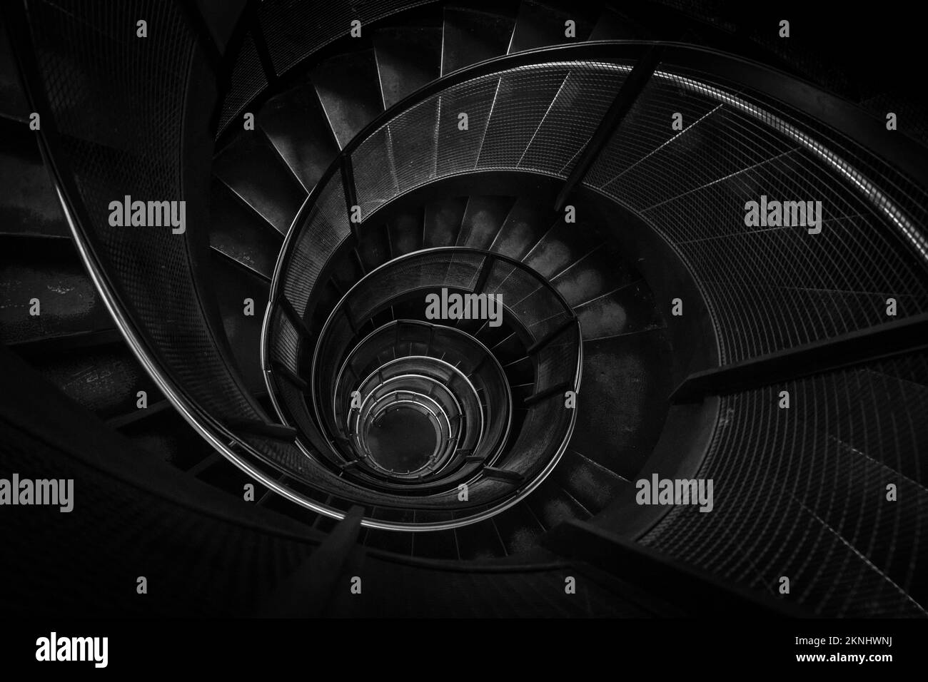 A greyscale high angle shot of spiral stairs with metal fences Stock ...