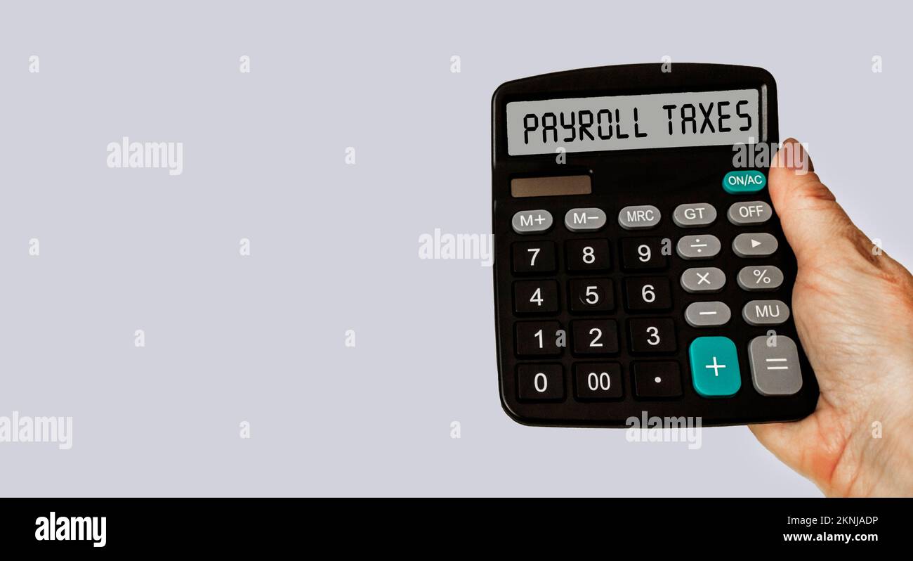 Payroll taxes concept on calculator display. A woman's hand is holding ...