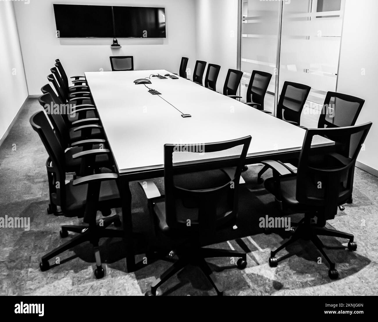A view of a modern, empty boardroom with a table and chairs in grayscale Stock Photo - Alamy
