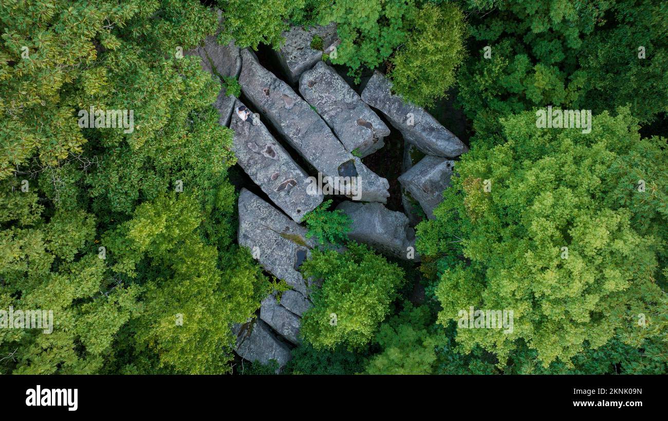 An aerial view of huge rocks isolated in a forest with dense green ...