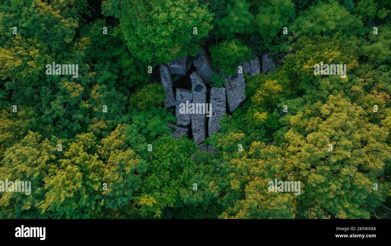 An aerial view of huge rocks isolated in a forest with dense green ...