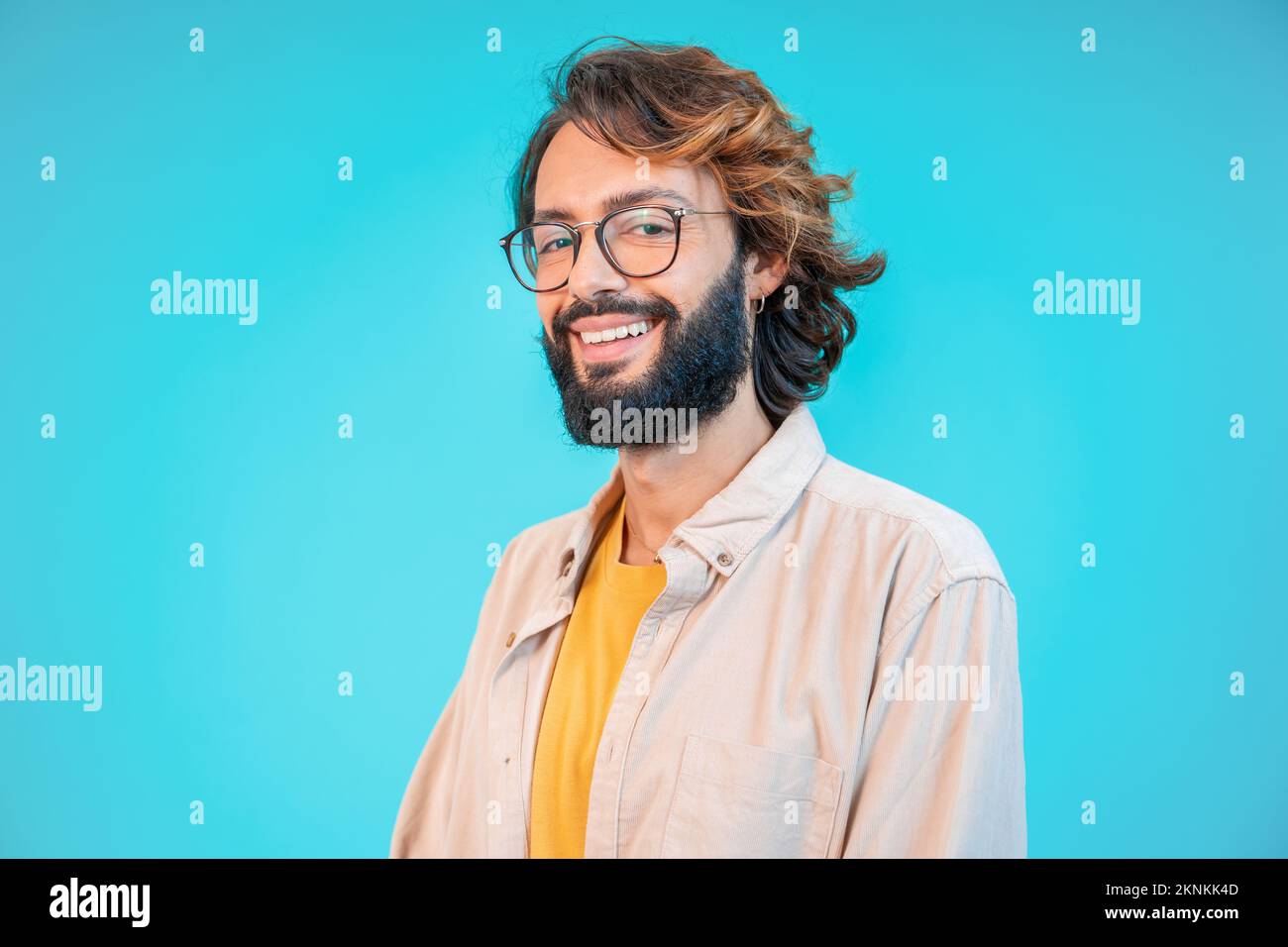 Young handsome man with beard and glasses over blue background happy ...