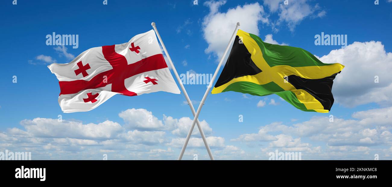 two crossed flags Jamaica and Georgia waving in wind at cloudy sky ...