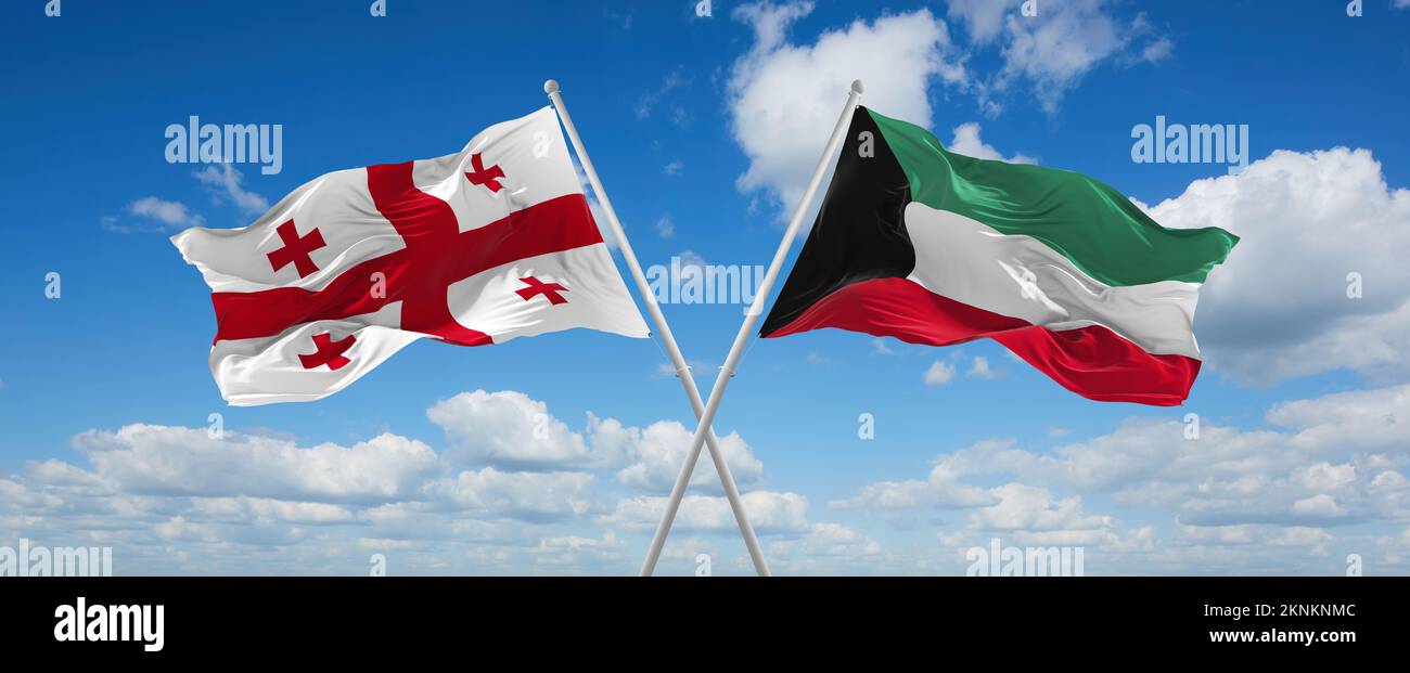 two crossed flags Kuwait and Georgia waving in wind at cloudy sky ...