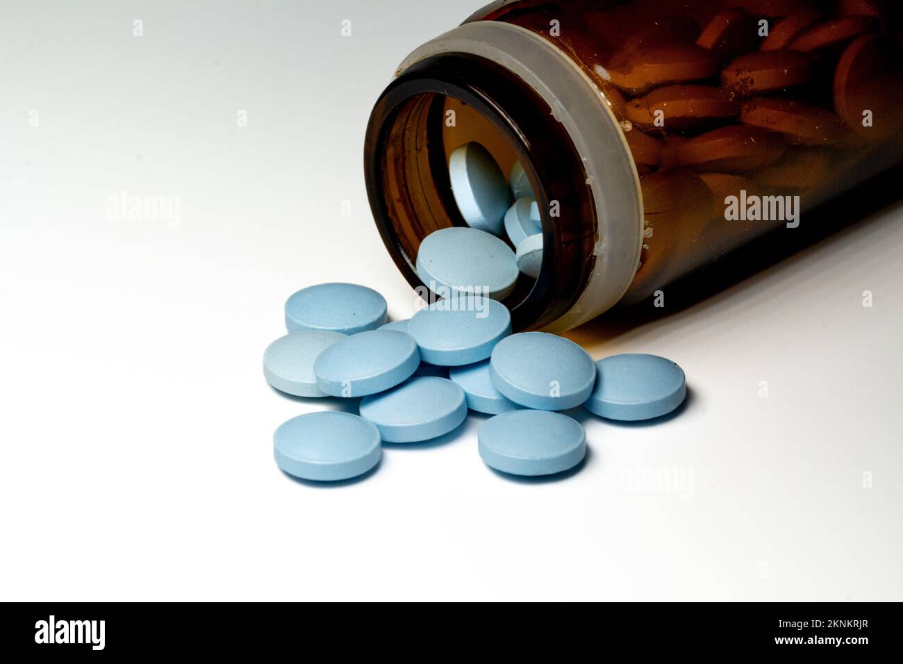 A close-up shot of blue medical tablets scattered from a jar isolated ...