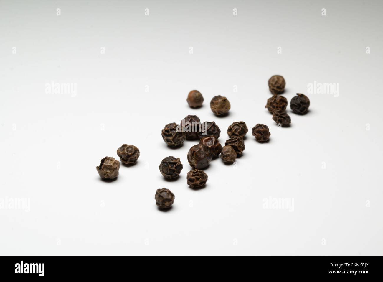 A close-up shot of black pepper balls isolated on a white background ...