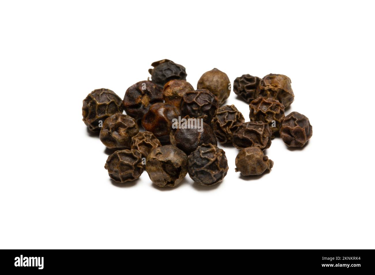 A close-up shot of black pepper balls isolated on a white background ...