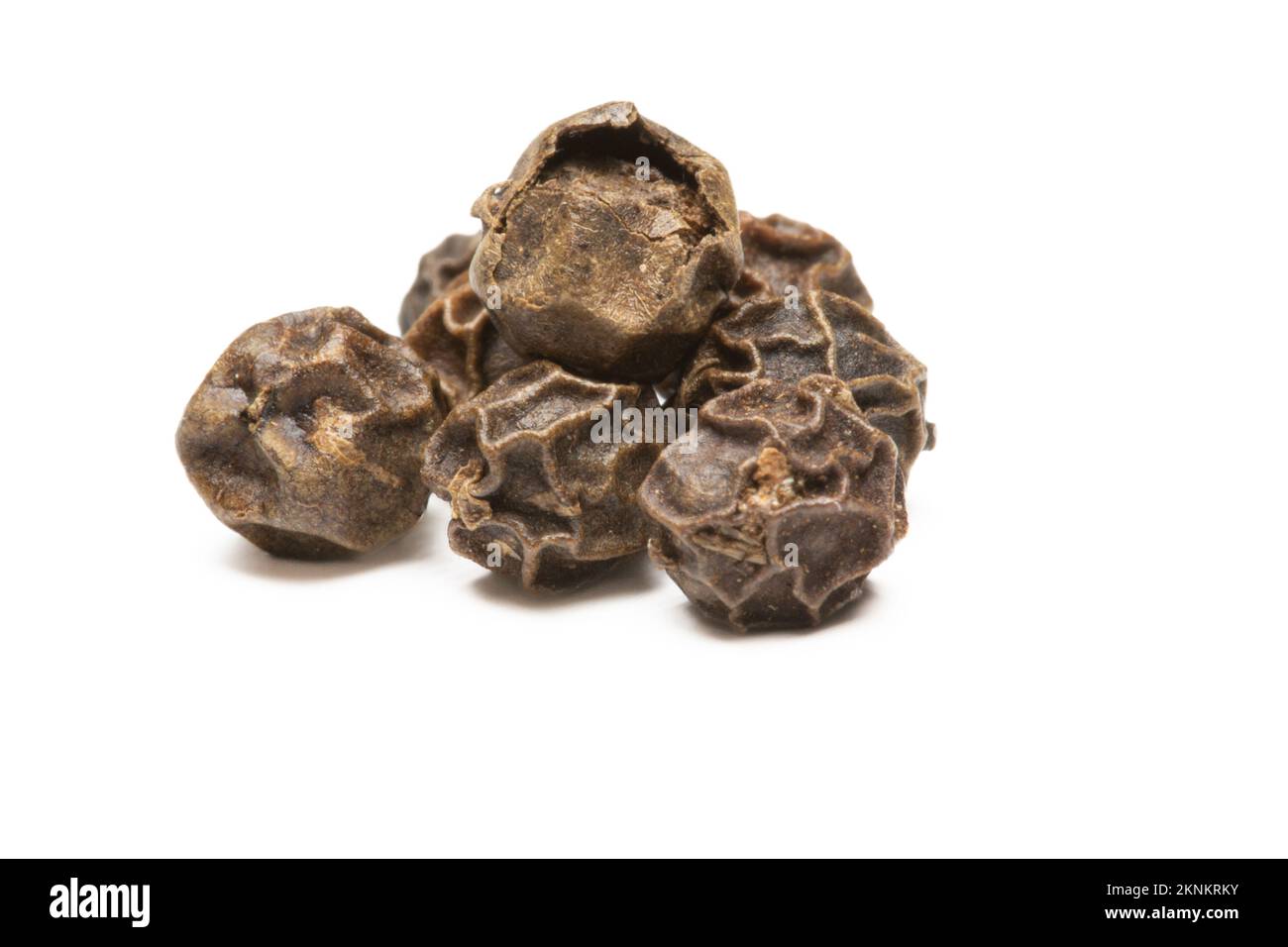 A close-up shot of black pepper balls isolated on a white background ...