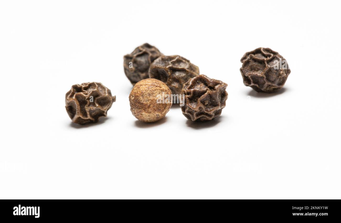 A close-up shot of black pepper balls isolated on a white background ...