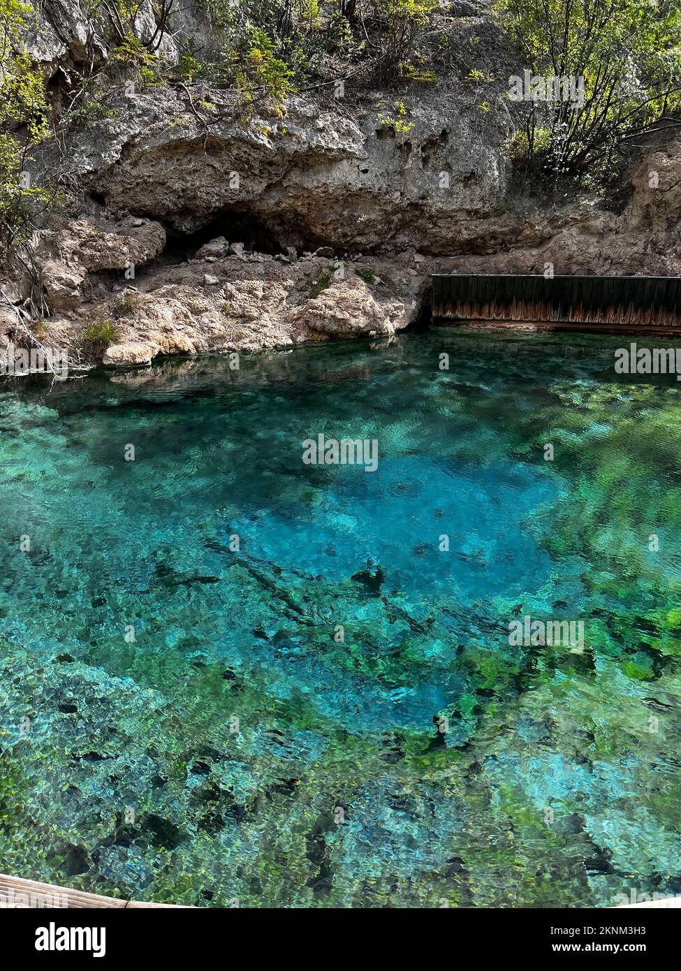 A vertical of a turquoise hot spring inside a rugged cave Stock Photo ...
