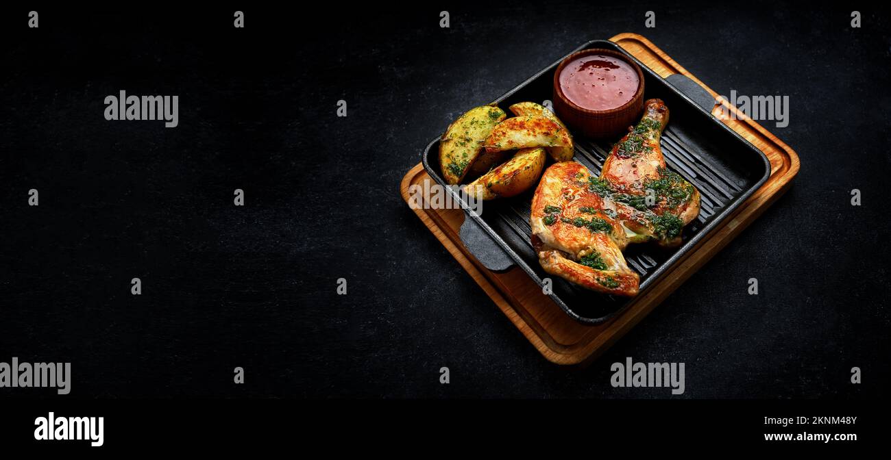 Fried half chicken with fried potatoes and spicy sauce, on a frying pan ...