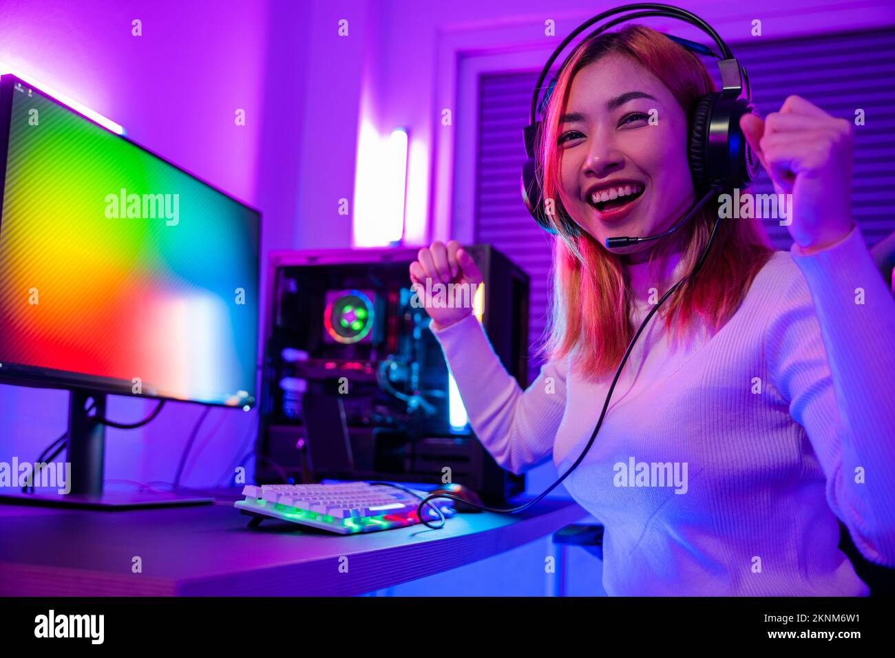 Happy Gamer young plays online video games computer she raises hands to ...