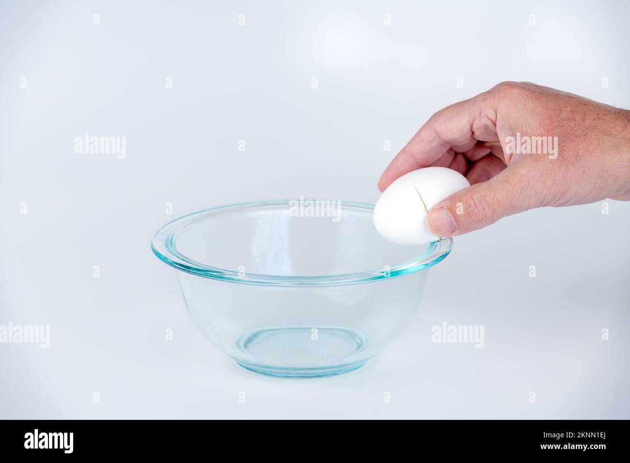 Glass bowl with a white egg cracked on the rim Stock Photo - Alamy