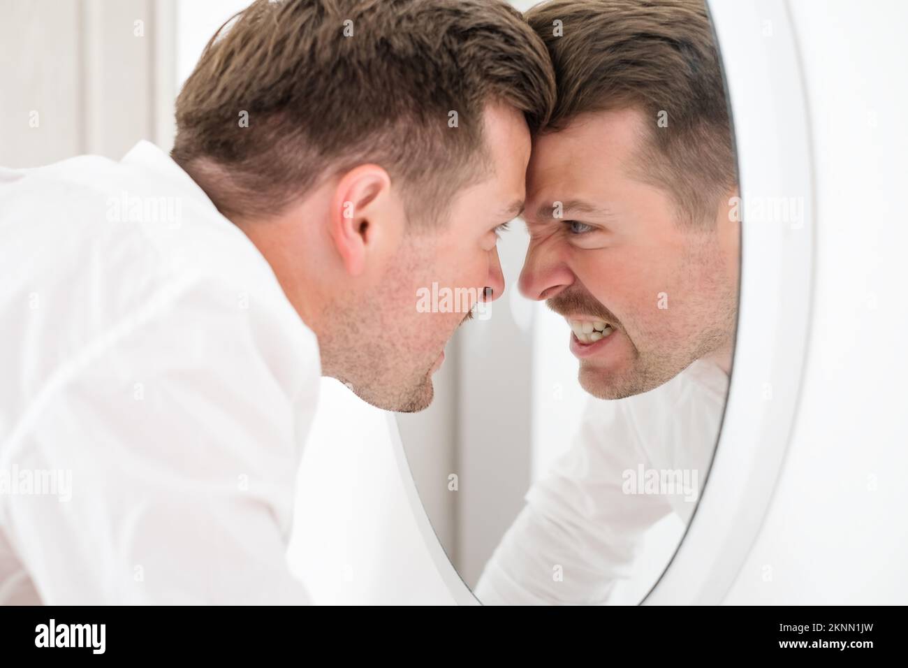 Caucasian man being angry on himself screaming on his reflection on the ...